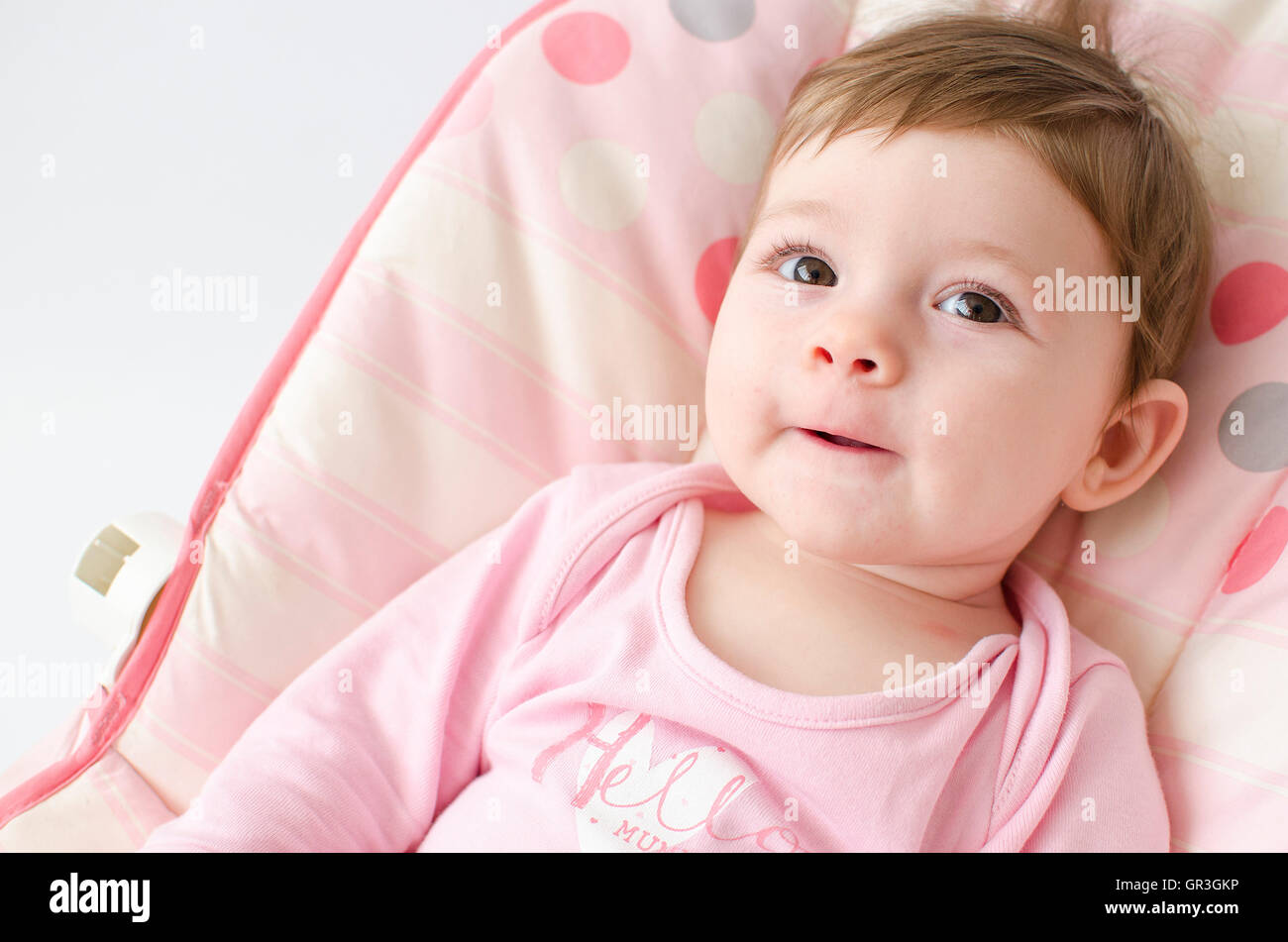 Beautiful Happy Baby Girl In A Bouncer Wearing Pink Onesie Stock Photo
