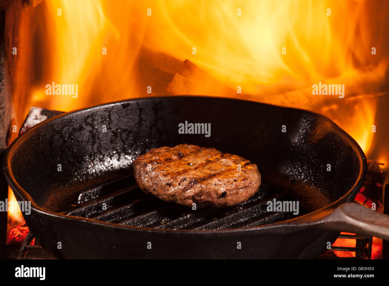 Burger cooked in pan with fire behind Stock Photo - Alamy