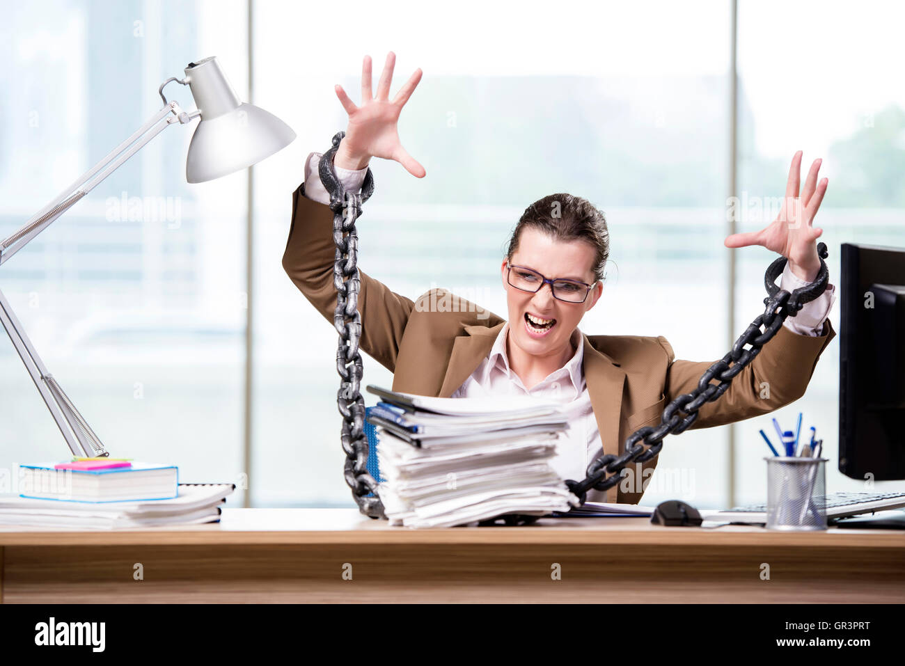 Woman chained to her working desk Stock Photo - Alamy