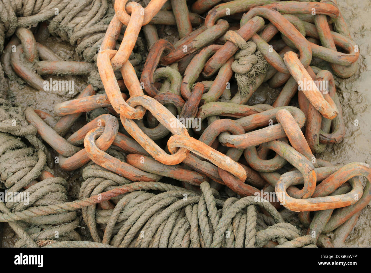 Rusty chain on shingle with muddy rope Stock Photo - Alamy