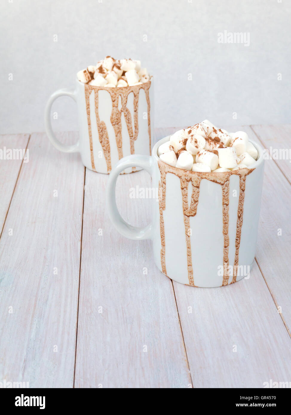 Hot cocoa with marshmallow and cocoa powder topping in white mugs with ...