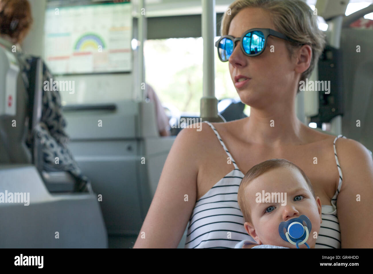 Mother with her baby boy over her legs on urban bus Stock Photo - Alamy
