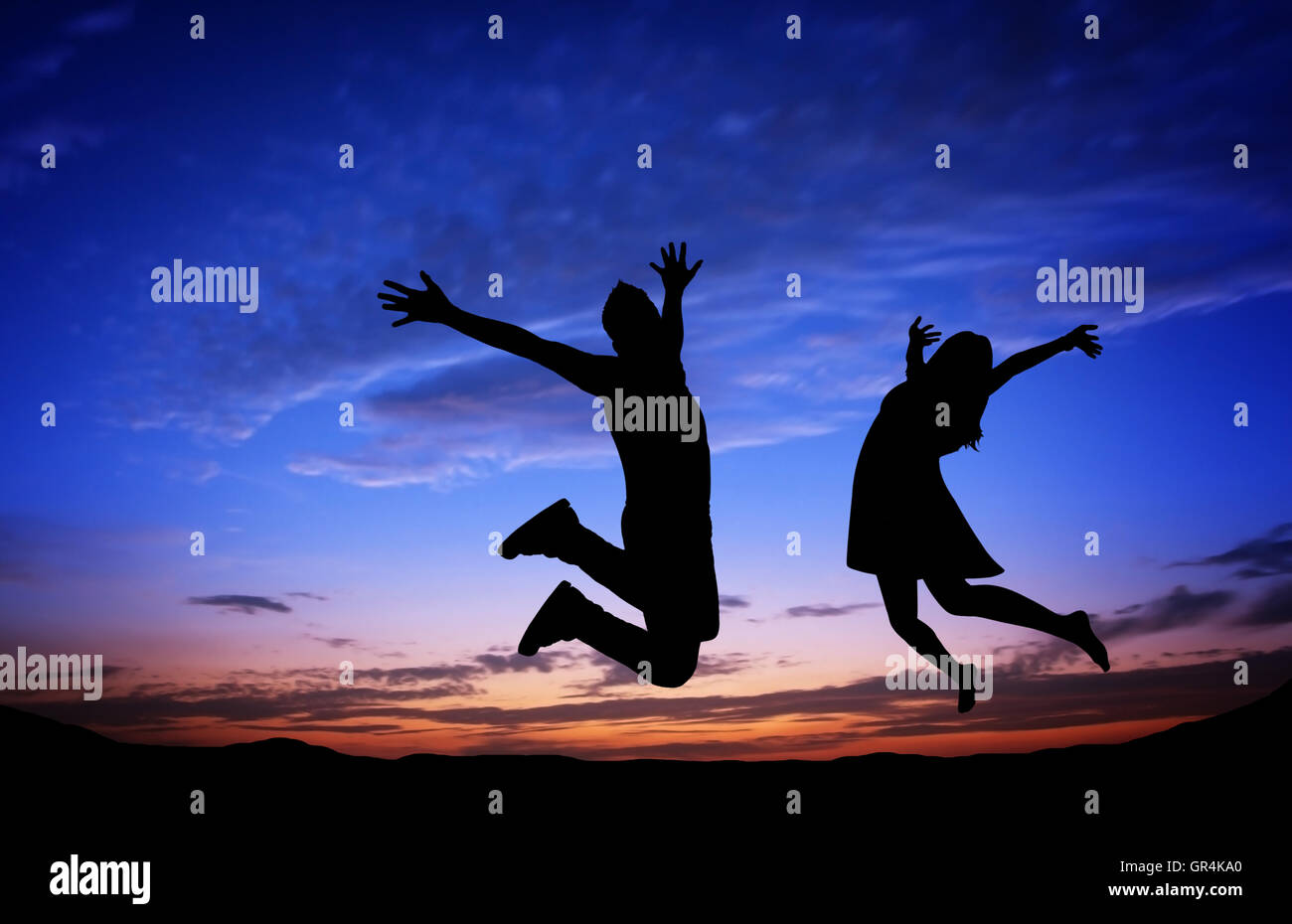 Silhouettes of couple jumping on sunset background Stock Photo - Alamy