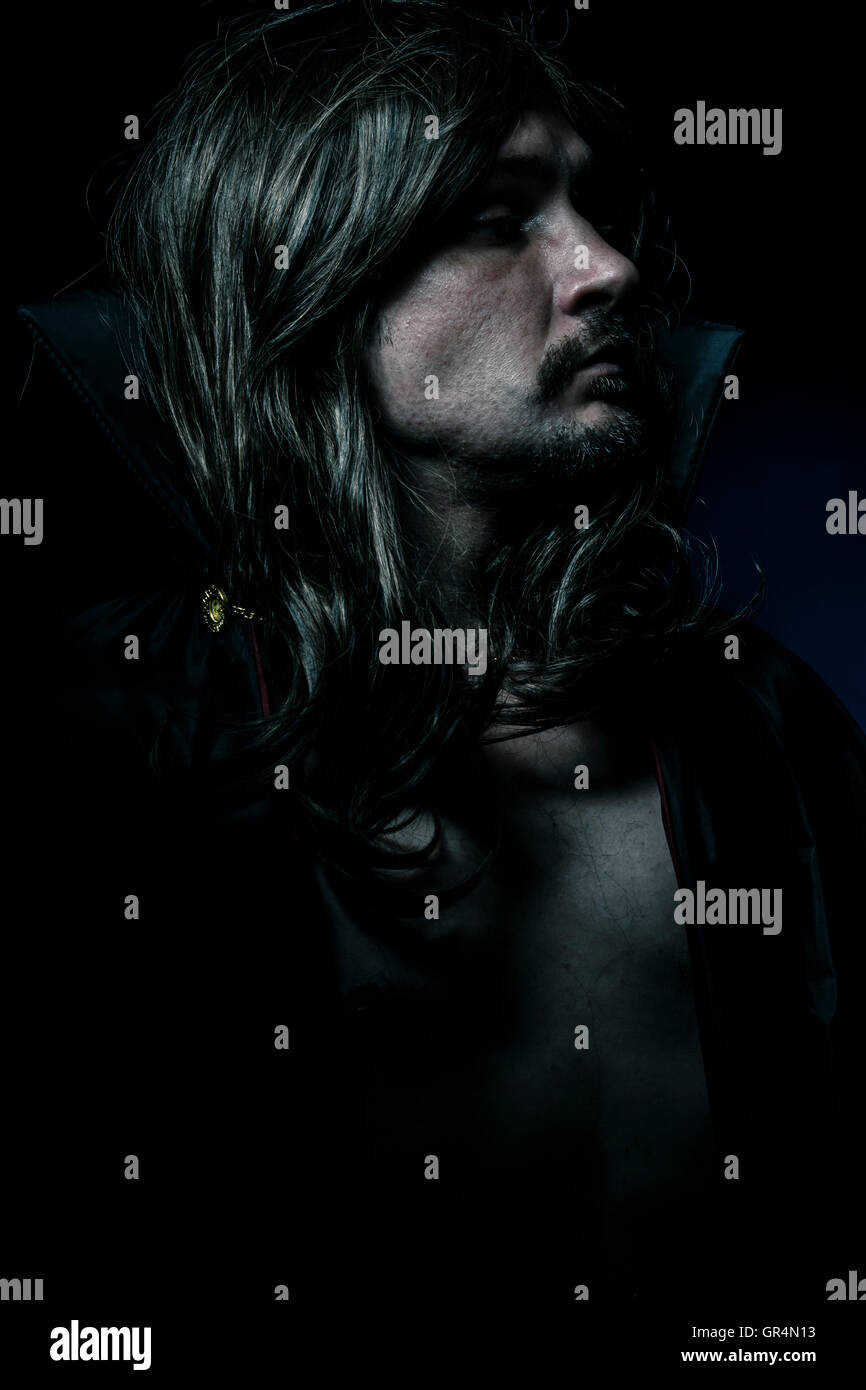 Vampire with black coat and long hair, blue light Stock Photo - Alamy