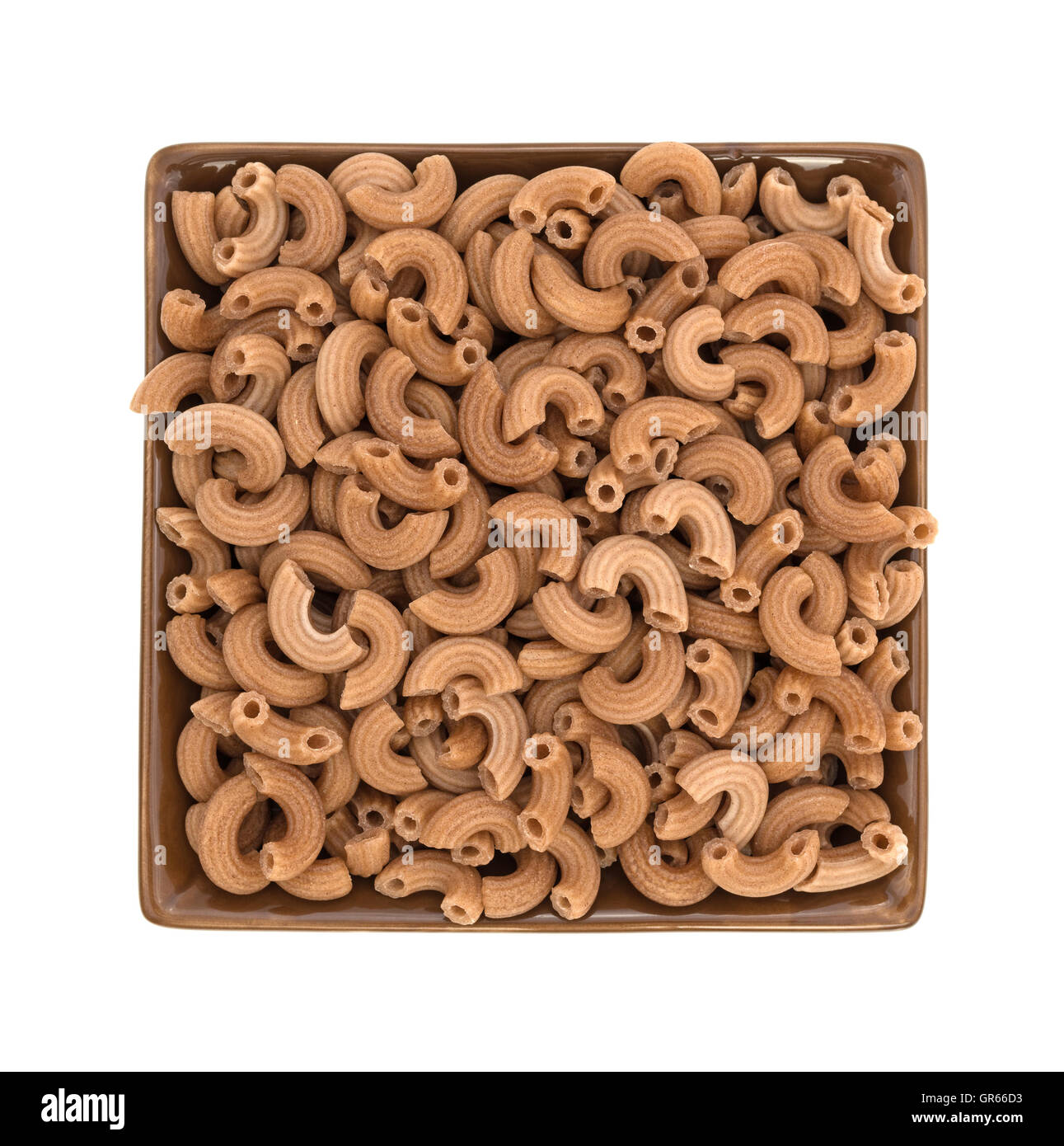 Top view of red rice elbow shaped pasta in a brown square dish isolated ...