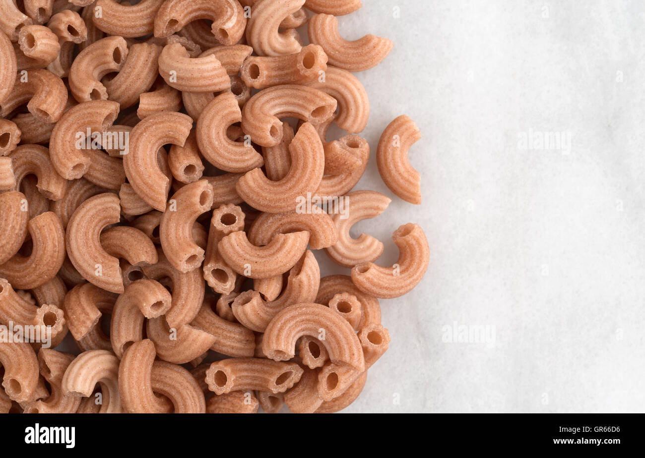 Top view of red rice elbow shaped pasta on gray marble cutting board ...