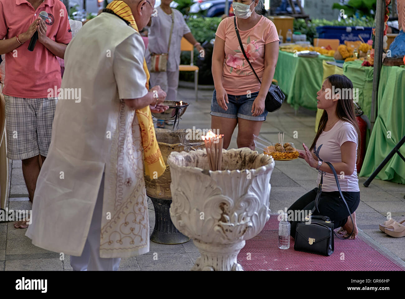 Thailand merit making. Woman kneeling and offering merit at a Buddhist ...