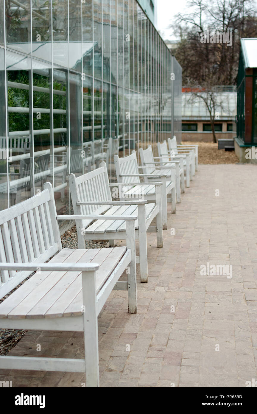 Row of white benches near glass building Stock Photo - Alamy