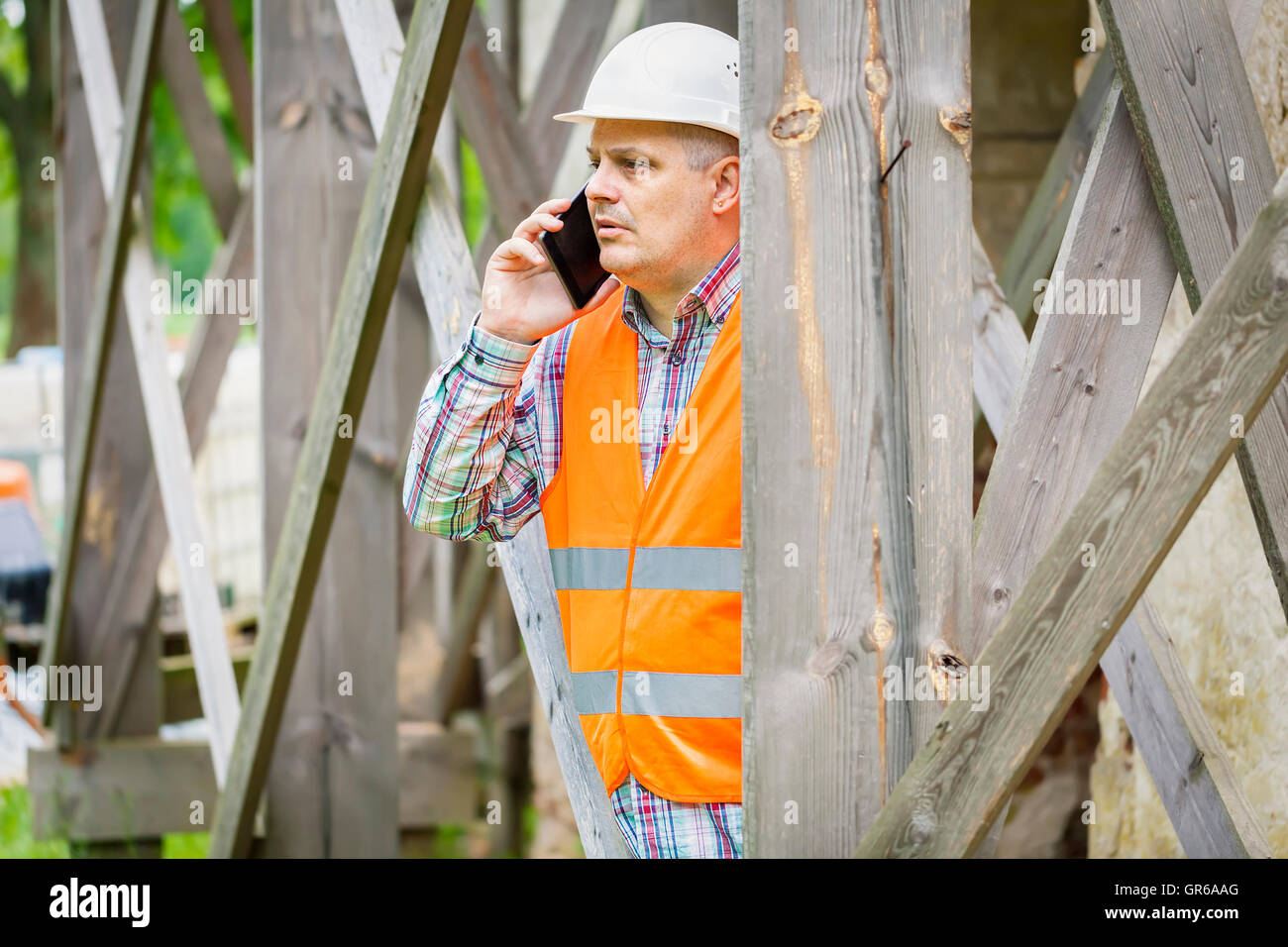 Construction worker looking through scaffolding Stock Photo - Alamy