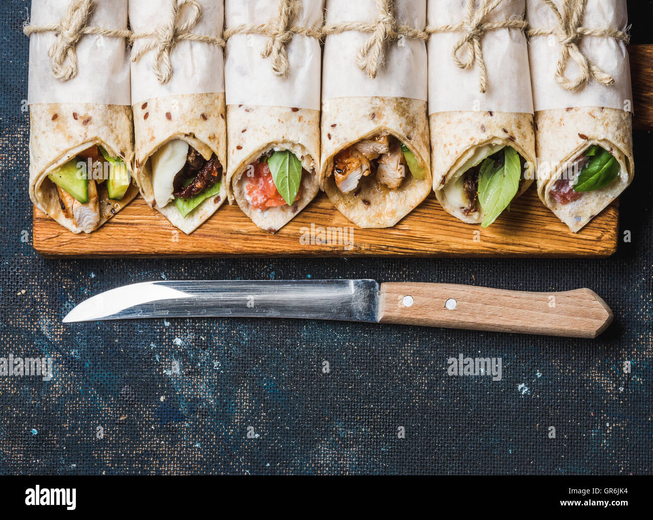 Tortilla wraps with different fillings on dark grey concrete background ...