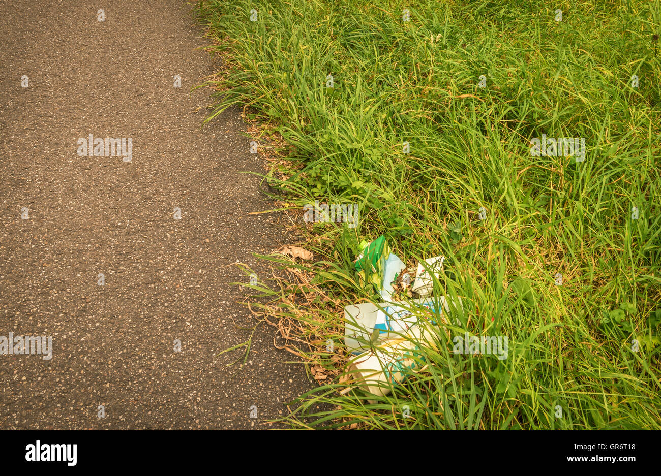 Trash on the side of the road in the grass Stock Photo - Alamy