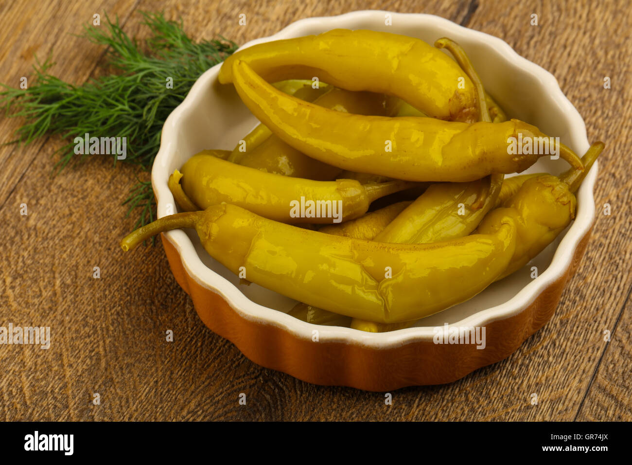 Pickled green pepperoni pepper in the bowl on wood background Stock ...