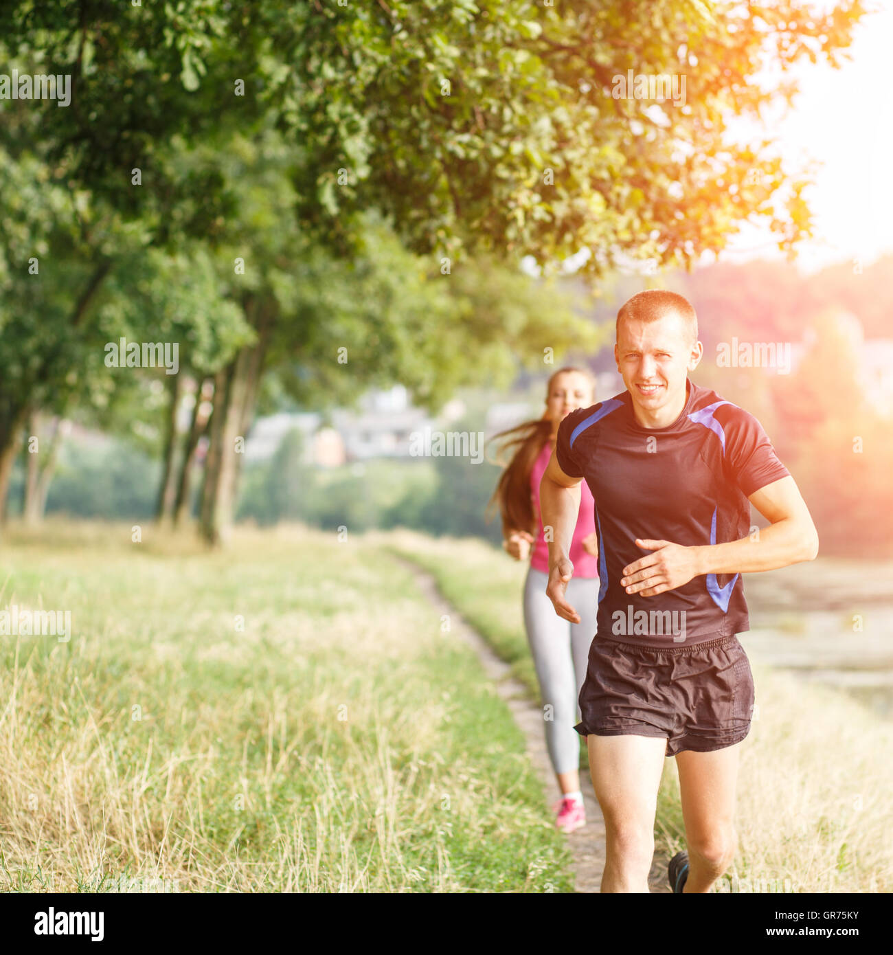Young athletic people jogging outdoor near pond. Man and woman doing ...
