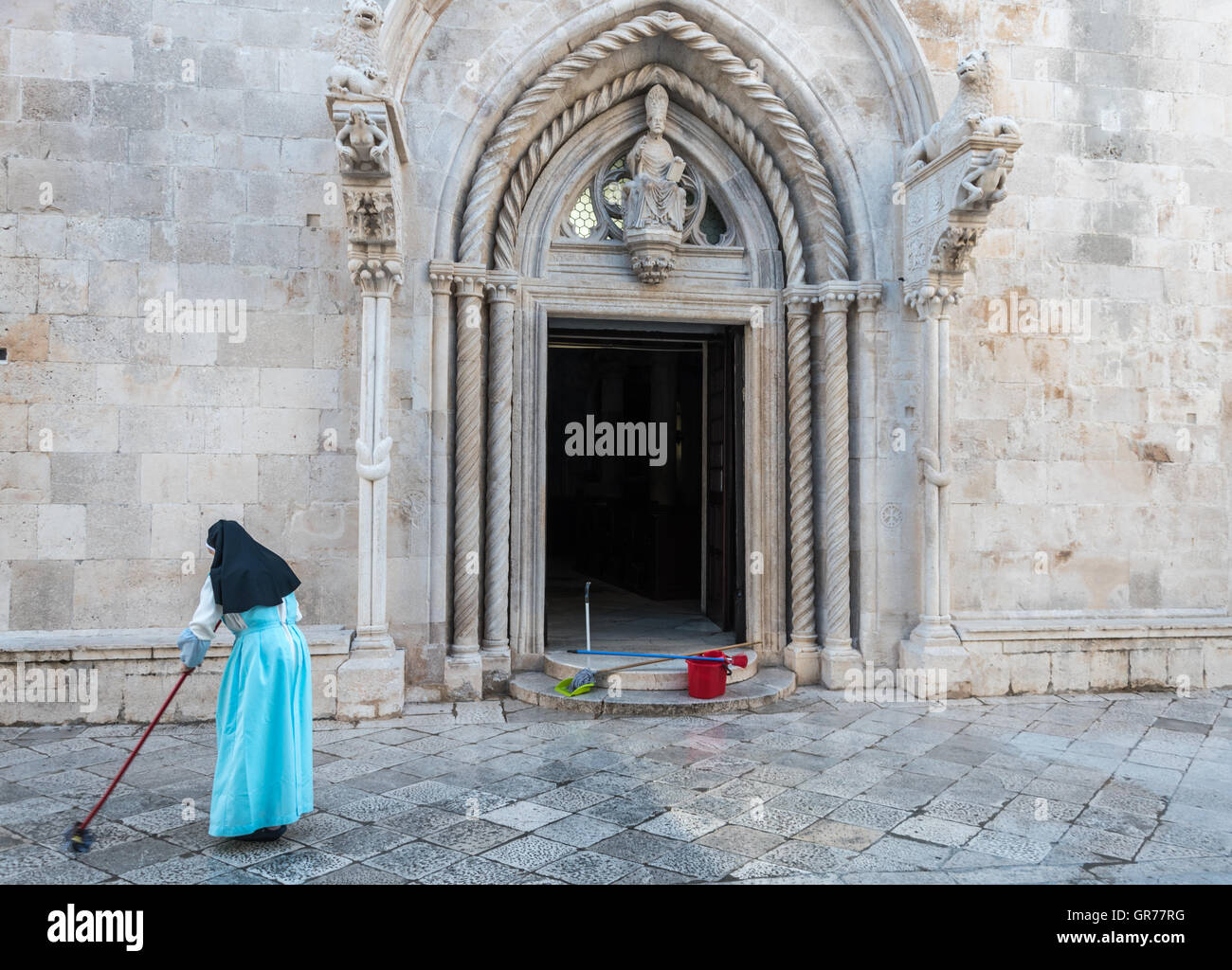 Nun cleaning street by Cathedral Sveti Marko Stock Photo - Alamy