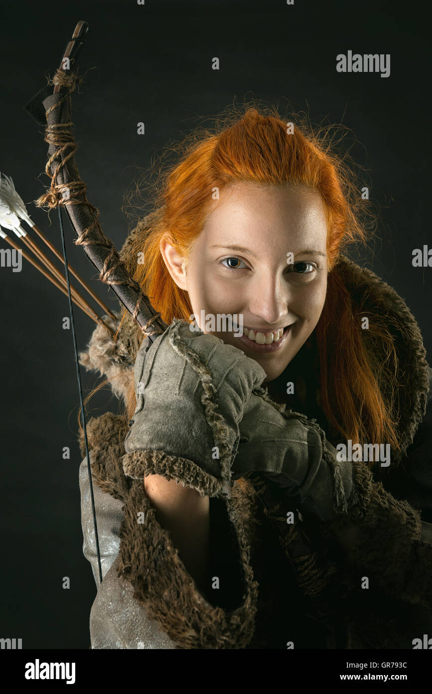girl archer in a costume with bow isolated in a dark background Stock ...