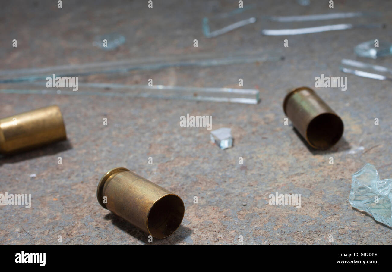 Handgun shells that have been shot on concrete with glass around Stock ...