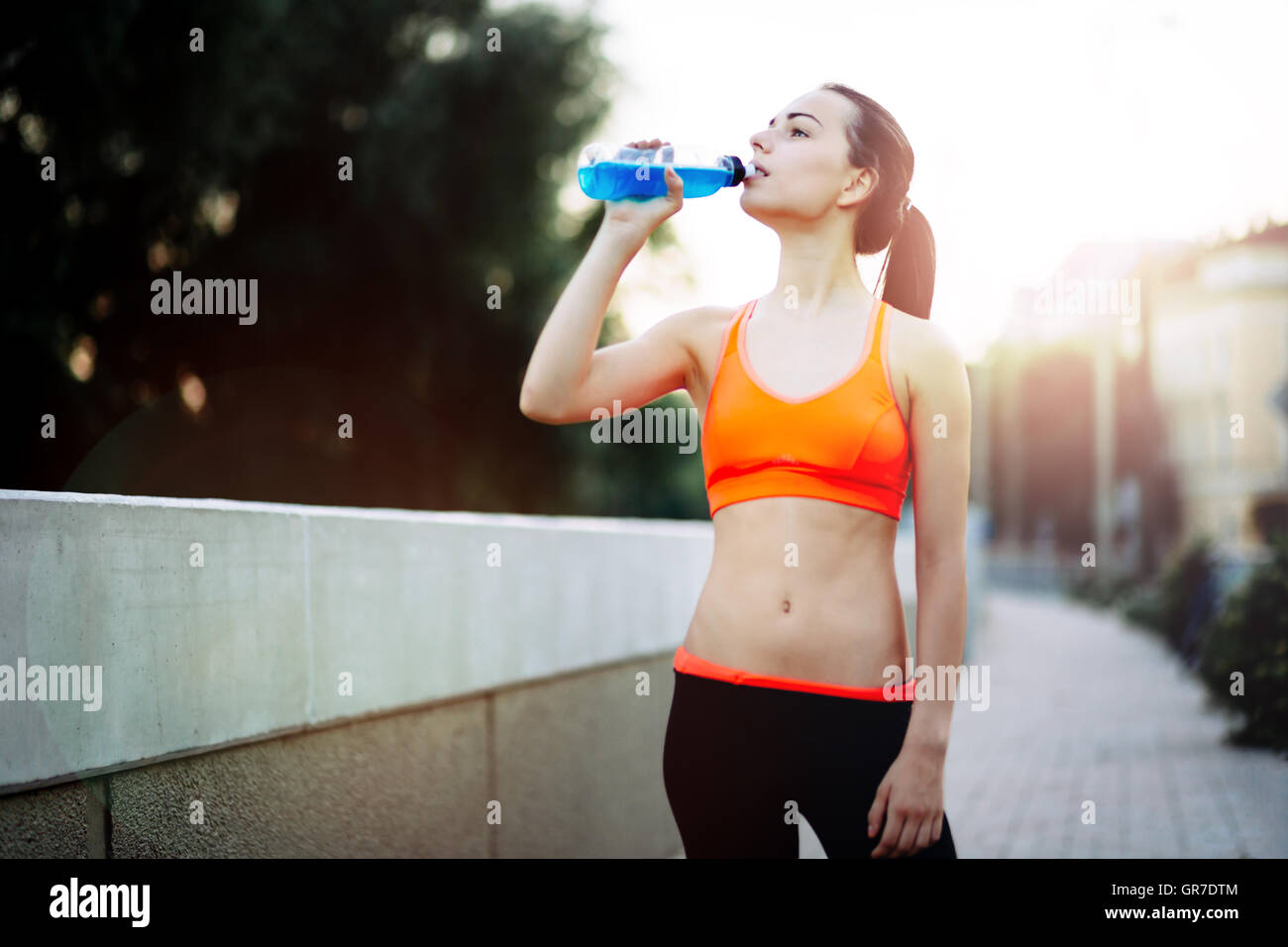 Female runner resting and drinking water Stock Photo - Alamy