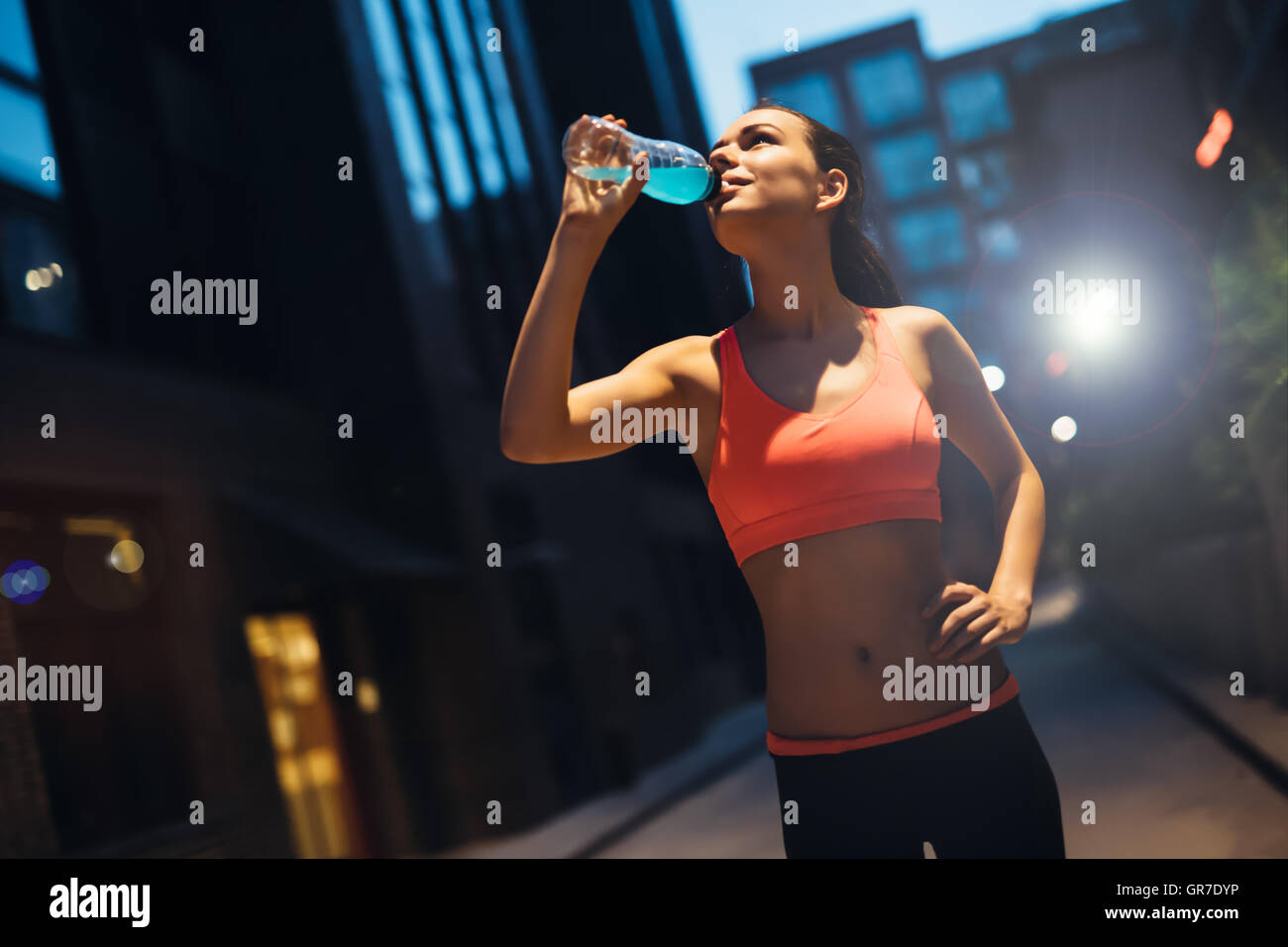 Female runner resting and drinking water Stock Photo - Alamy