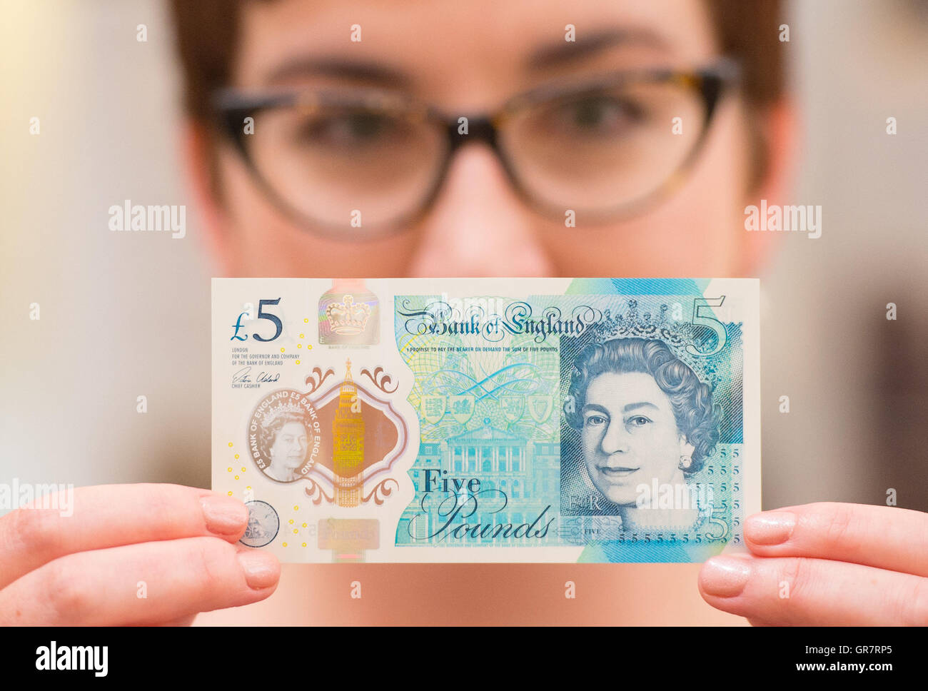 Curator Jenni Adam holds a new polymer five pound note at the opening ...