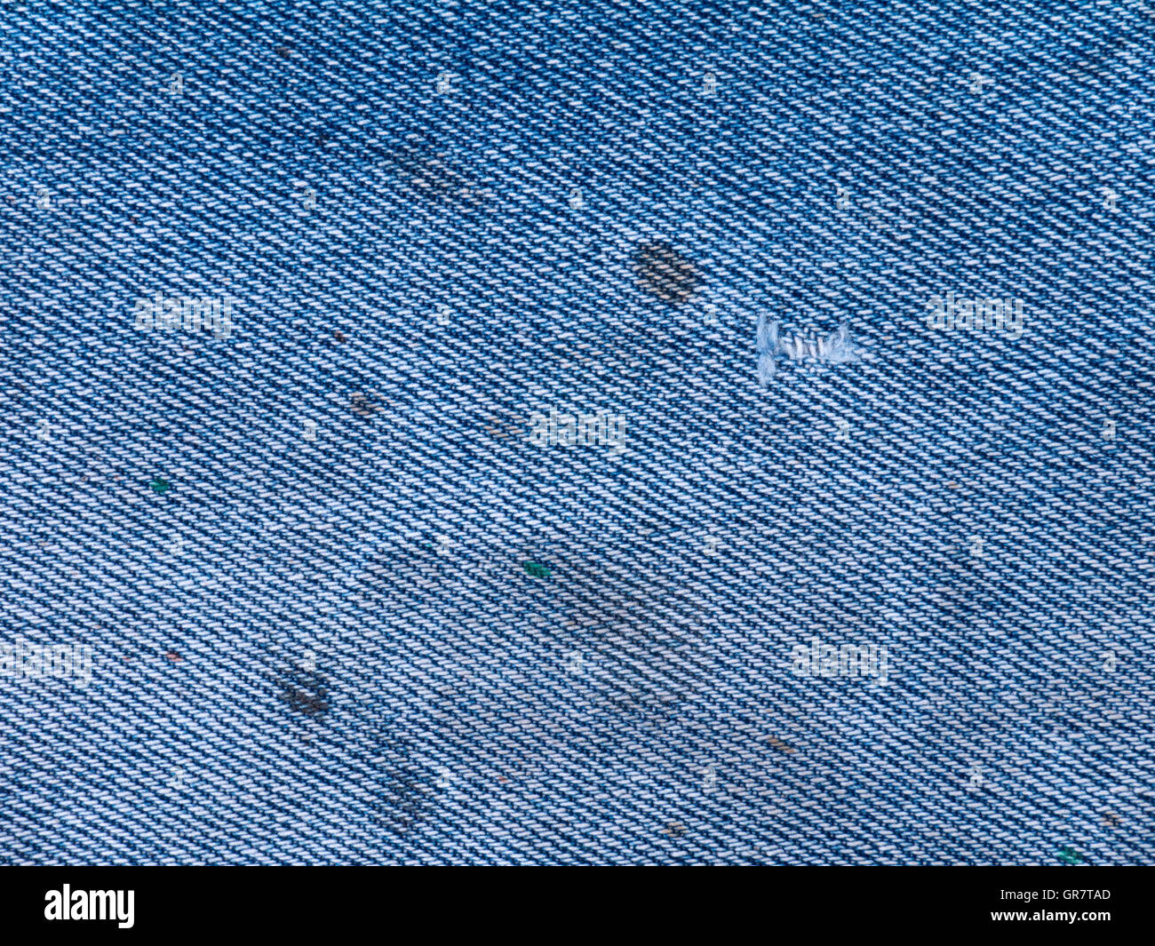 Old faded light blue denim with spots and hole background Stock Photo ...