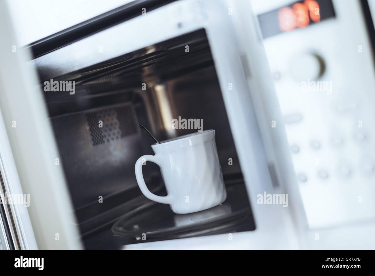 A White Cup With Spoon On Sale In The Microwave Oven With The Door Open ...