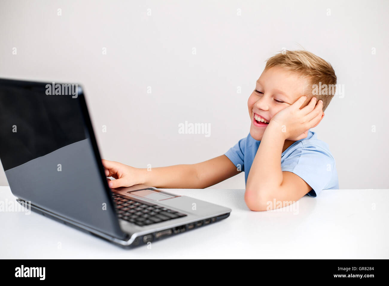 Blond boy looking at laptop Stock Photo - Alamy
