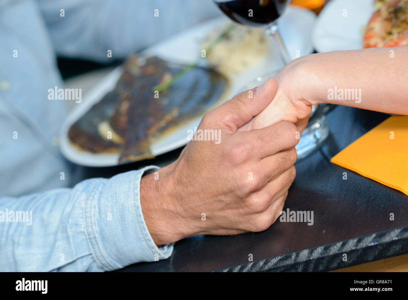Closeup of couple holding hand over meal Stock Photo - Alamy