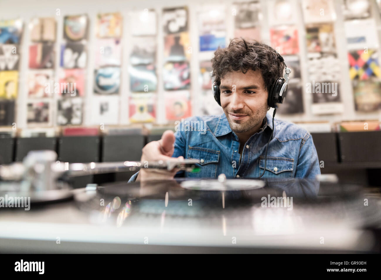 Man put the platinum arm on the turntable and listening the music with ...