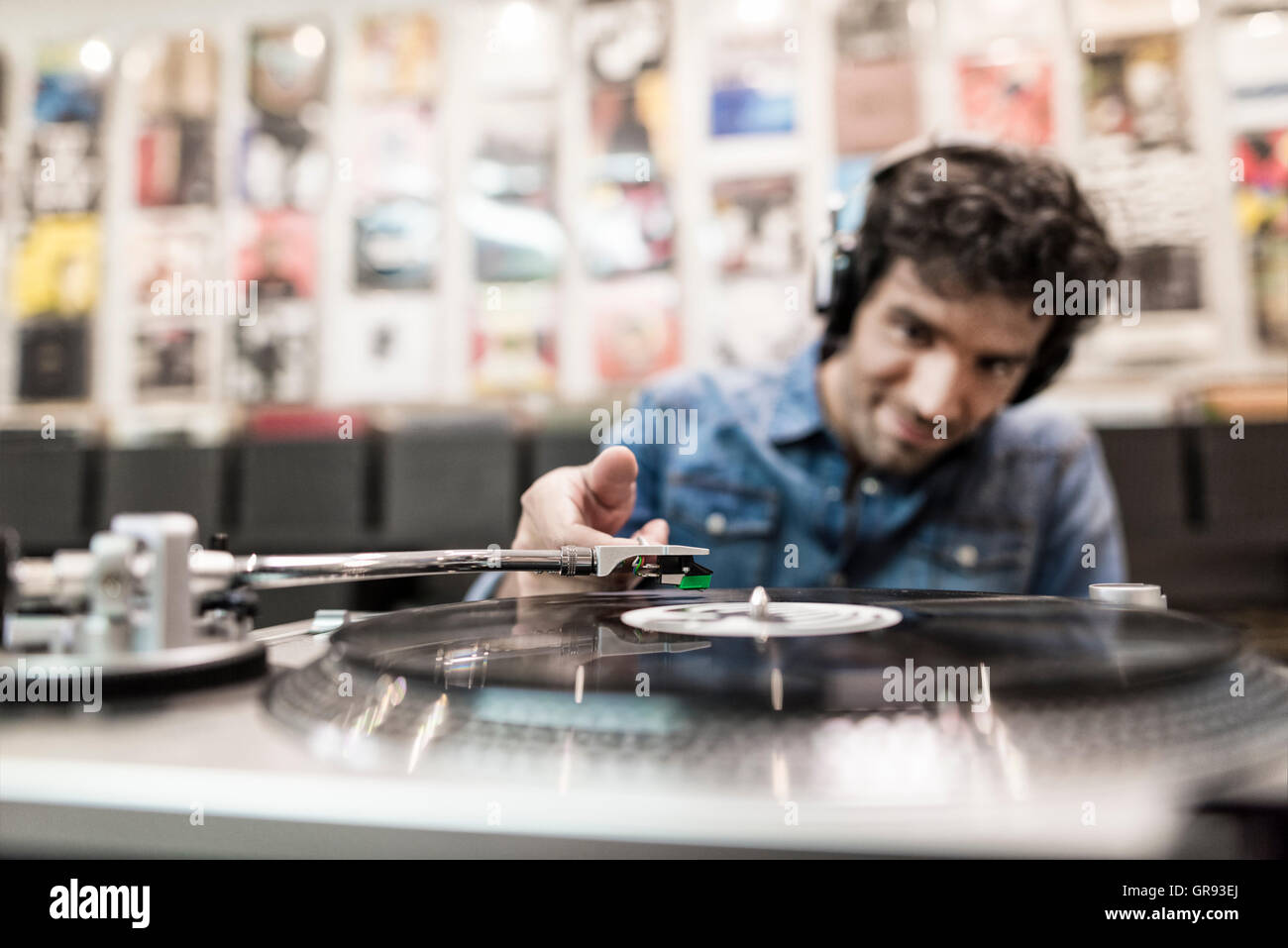 Man put the platinum arm on the turntable and listening the music with ...