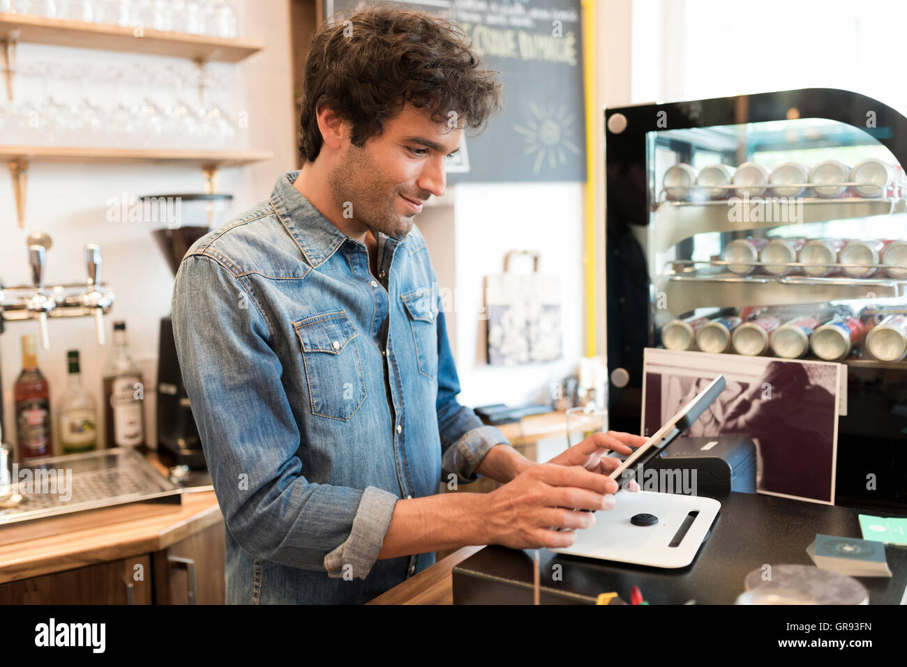In a restaurant the waiter prepares the bill on computer POS tablet pc ...