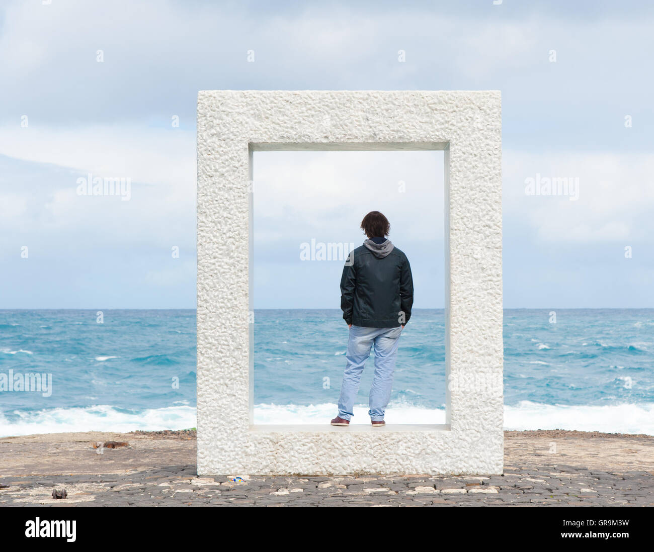 Young Man Standing In A Concrete Cuboid And Looks At The Sea Stock ...