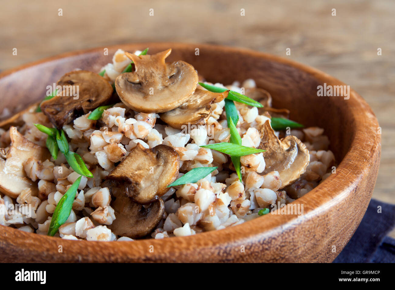 Russian traditional buckwheat with mushrooms and chives in wooden bowl ...