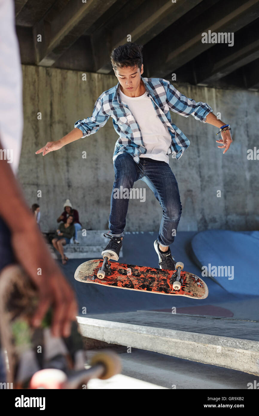 Focused teenage boy flipping skateboard at skate park Stock Photo - Alamy