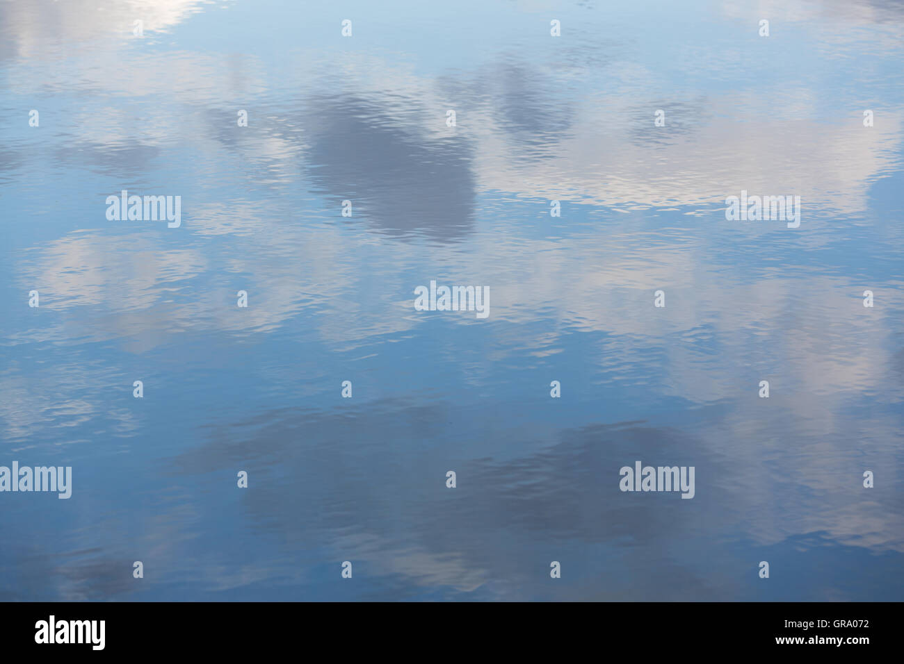 Reflection Of Clouds On Blue Water Stock Photo - Alamy