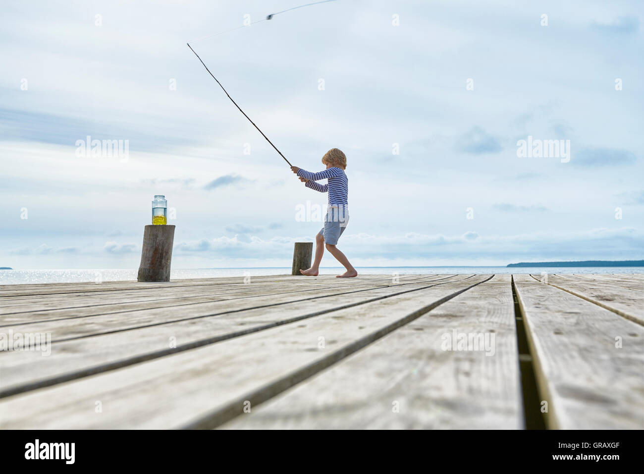 Boy fishing off lakeside dock Stock Photo - Alamy