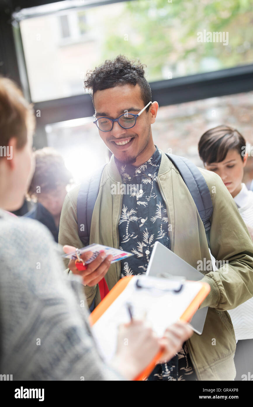 Smiling young man showing credentials at technology conference Stock ...