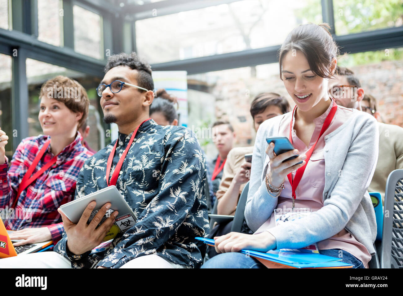 Woman texting with cell phone in audience at technology conference ...