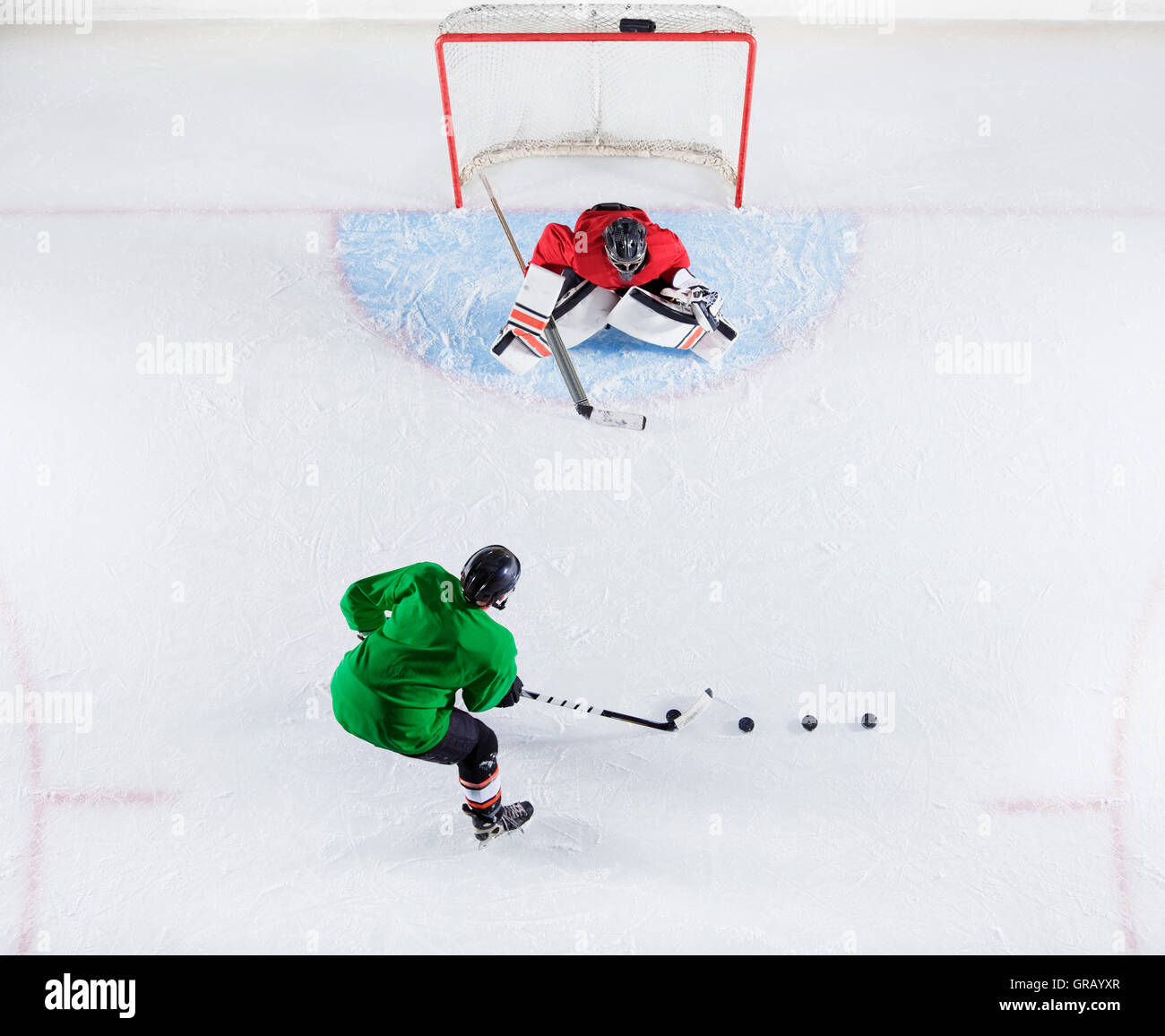 Overhead view hockey player practicing with goalie shooting puck at ...