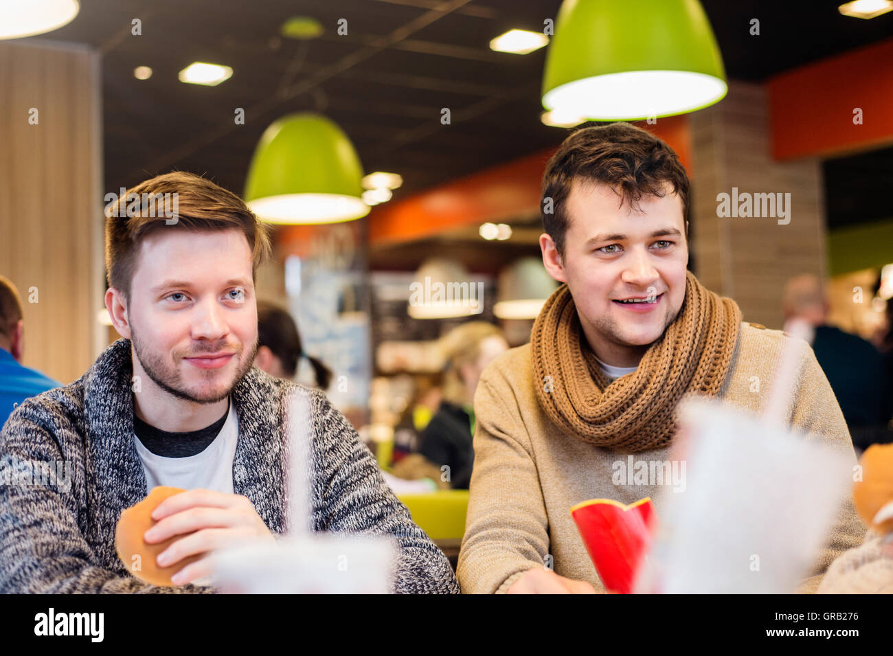 Two men eating out in fast food restaurant, talking Stock Photo - Alamy
