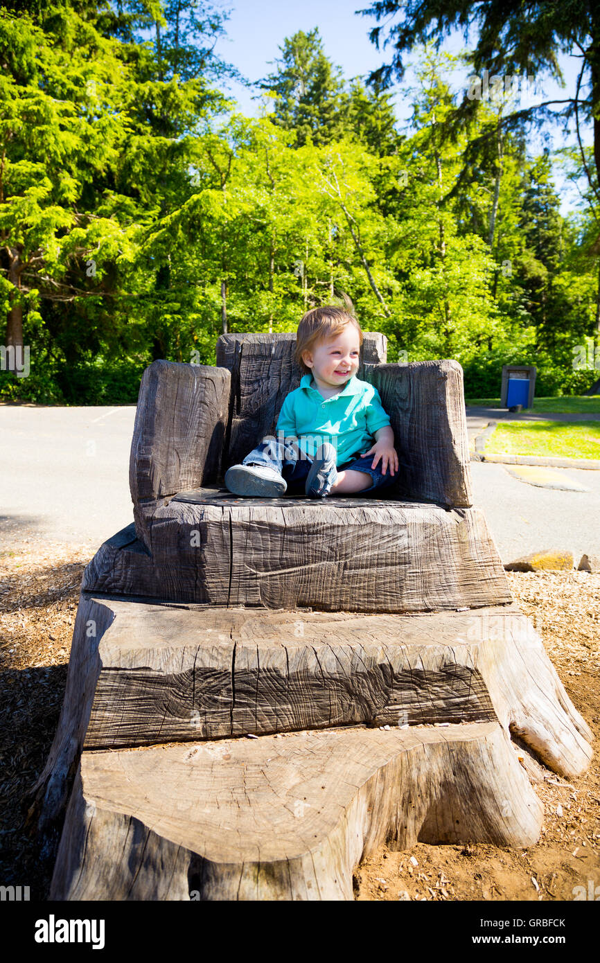 Boy Sitting on Stump Chair Stock Photo - Alamy