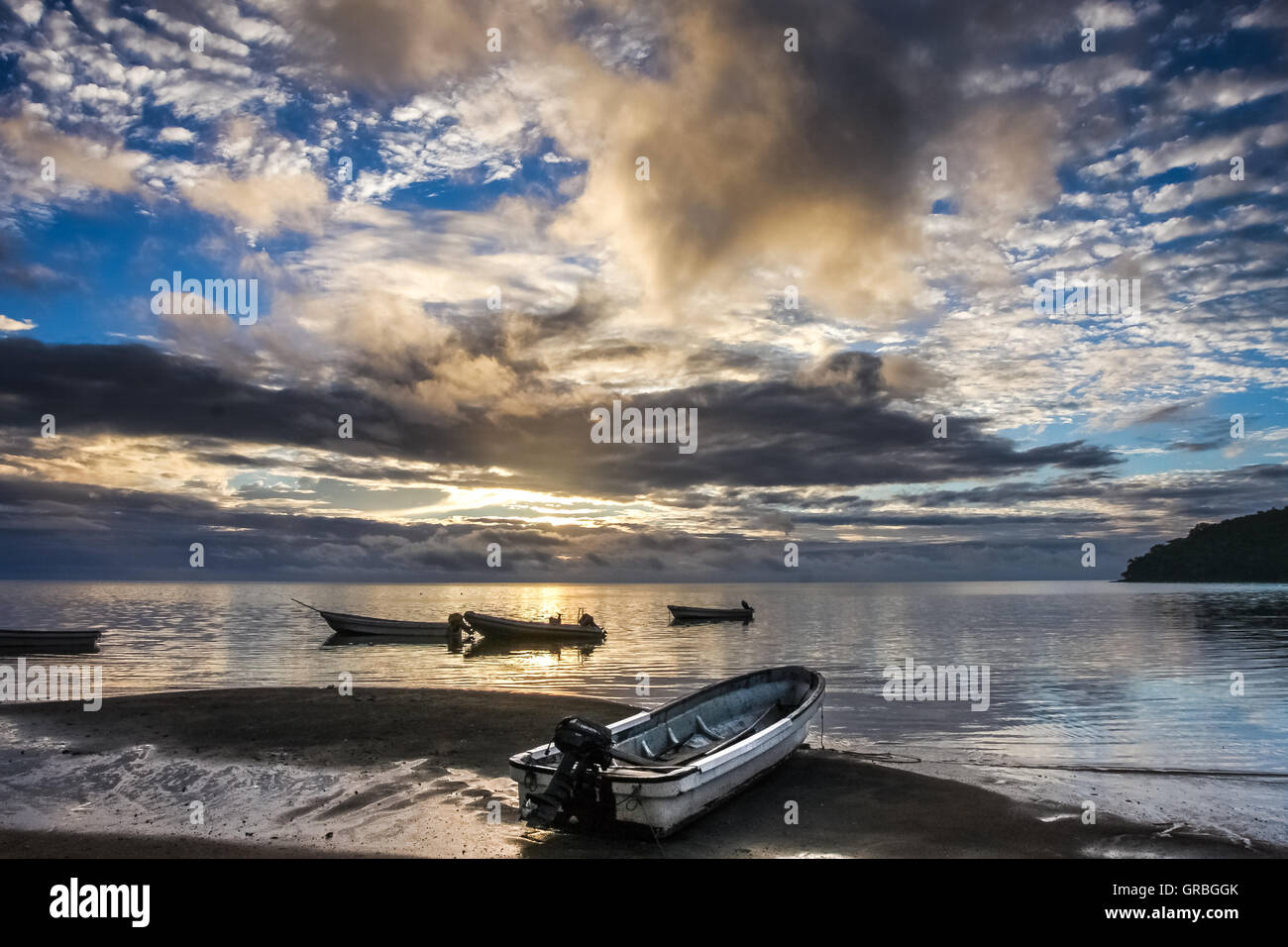 Scenic ocean sunset with small boats in foreground Stock Photo - Alamy