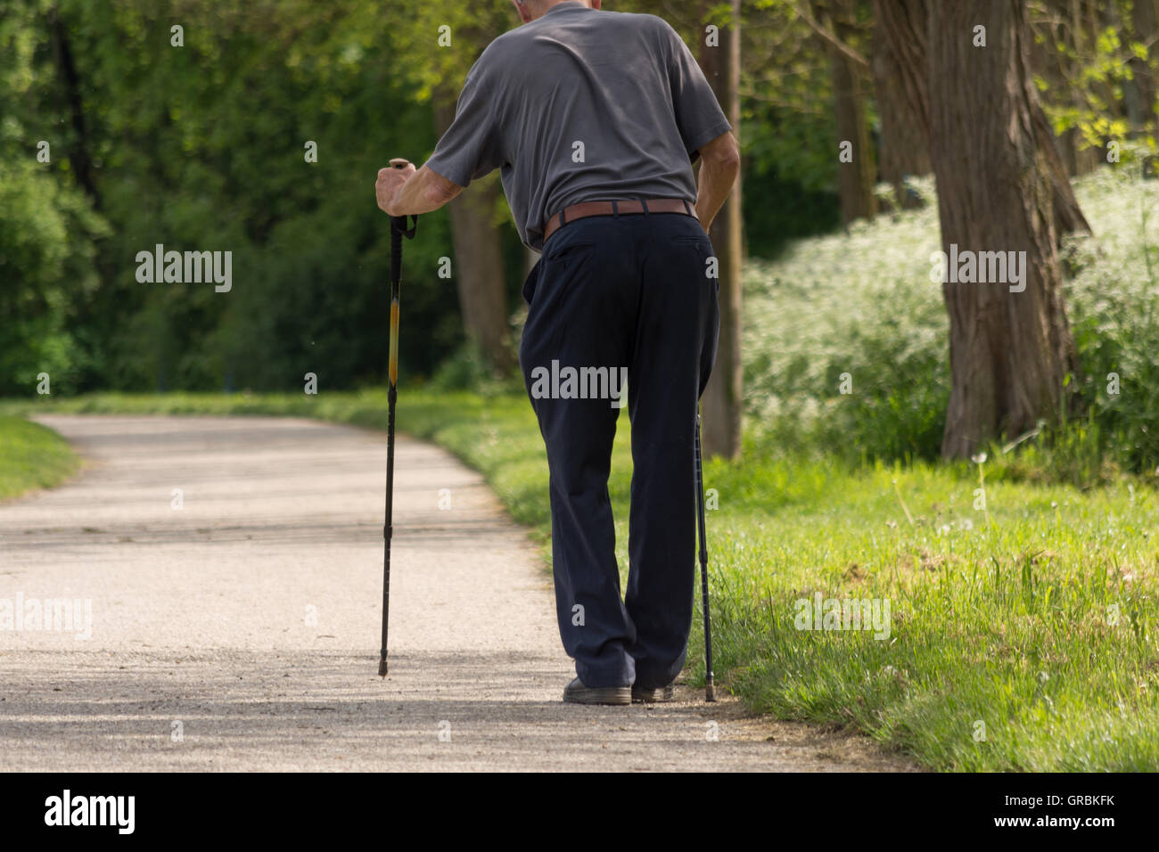 Frail Man Walking With Difficulty With Walking Sticks Stock Photo - Alamy