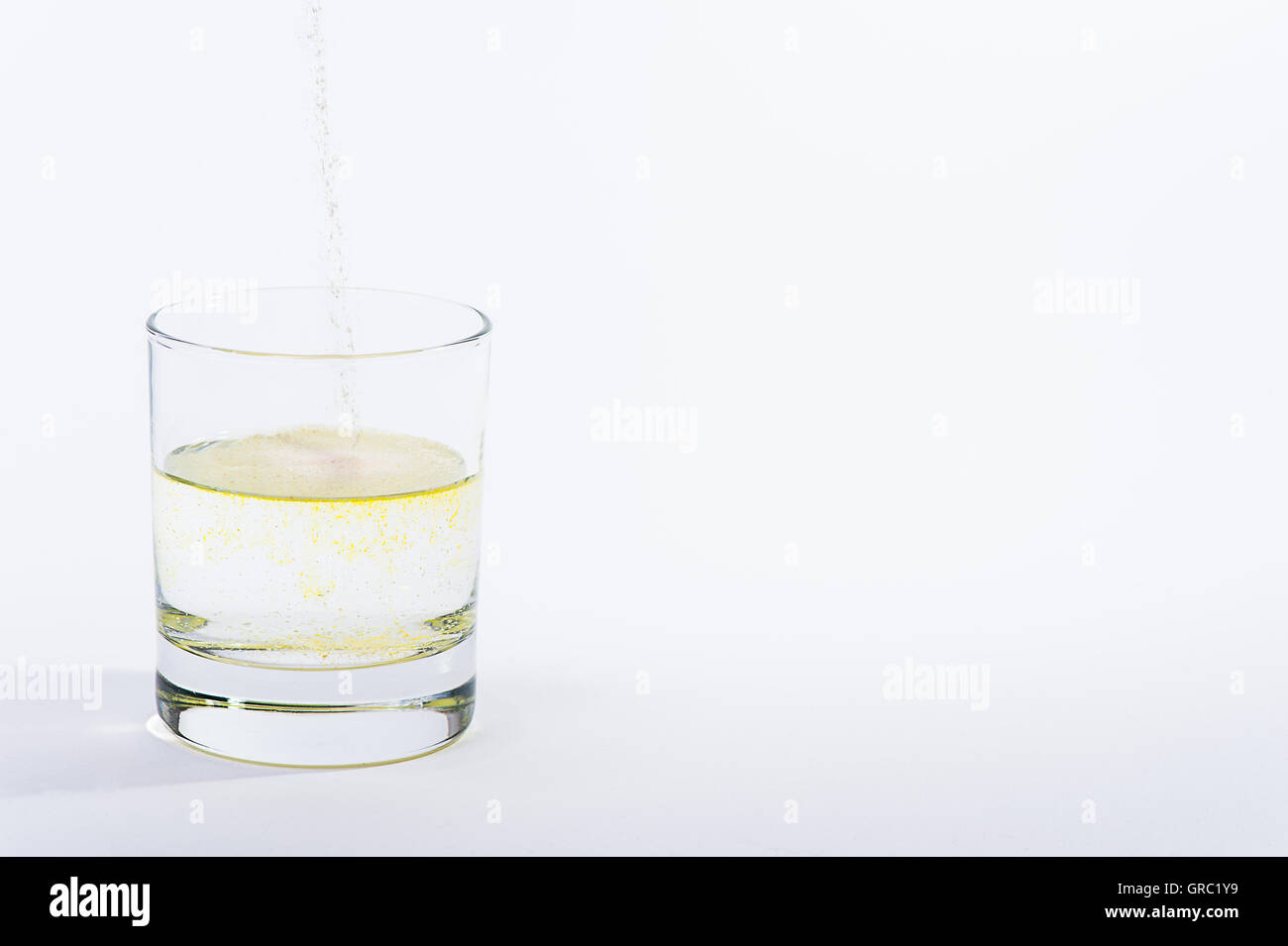 Yellow Powder Is Poured Into The Water Glass Stock Photo - Alamy