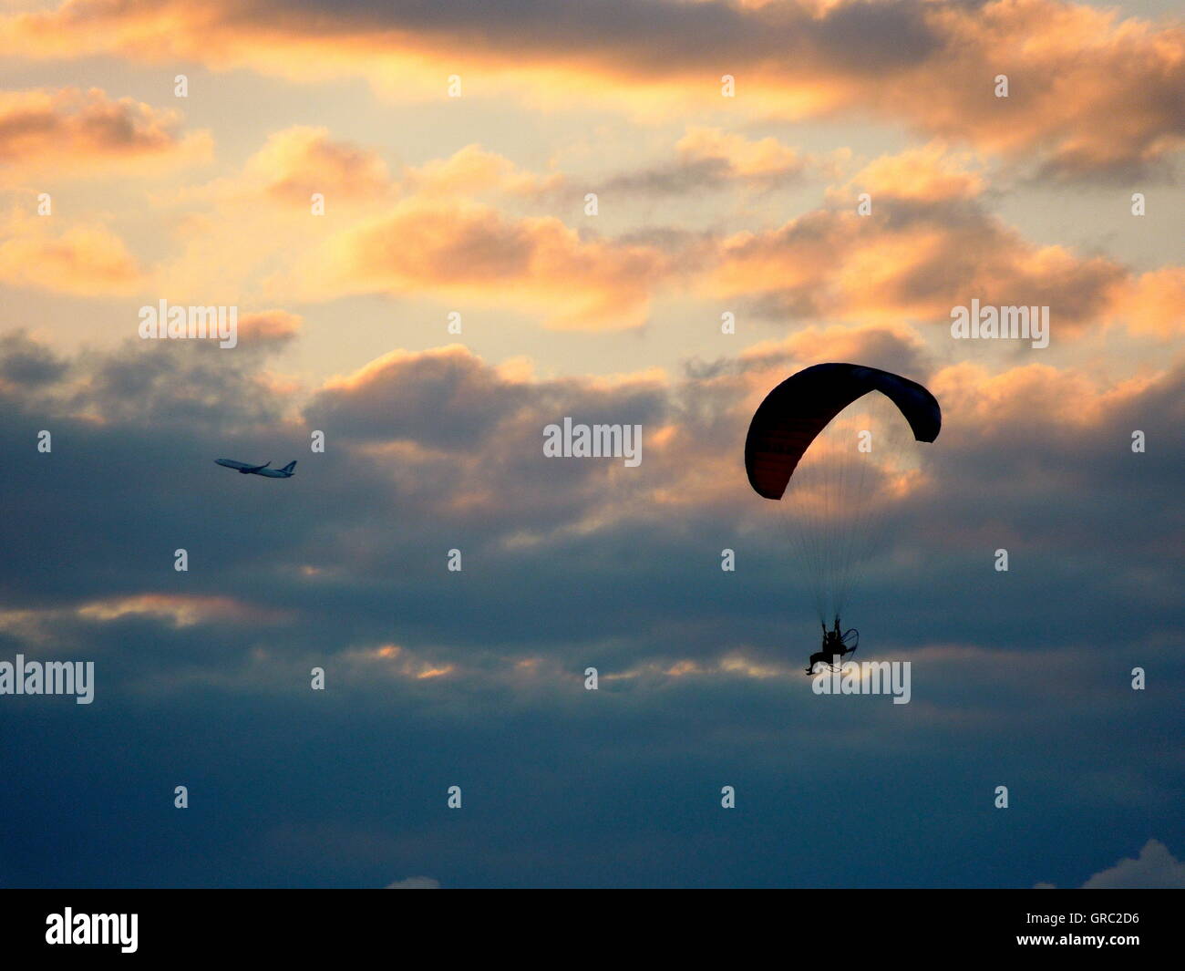 Flying Airplane And Paraglider At Sunset Stock Photo - Alamy