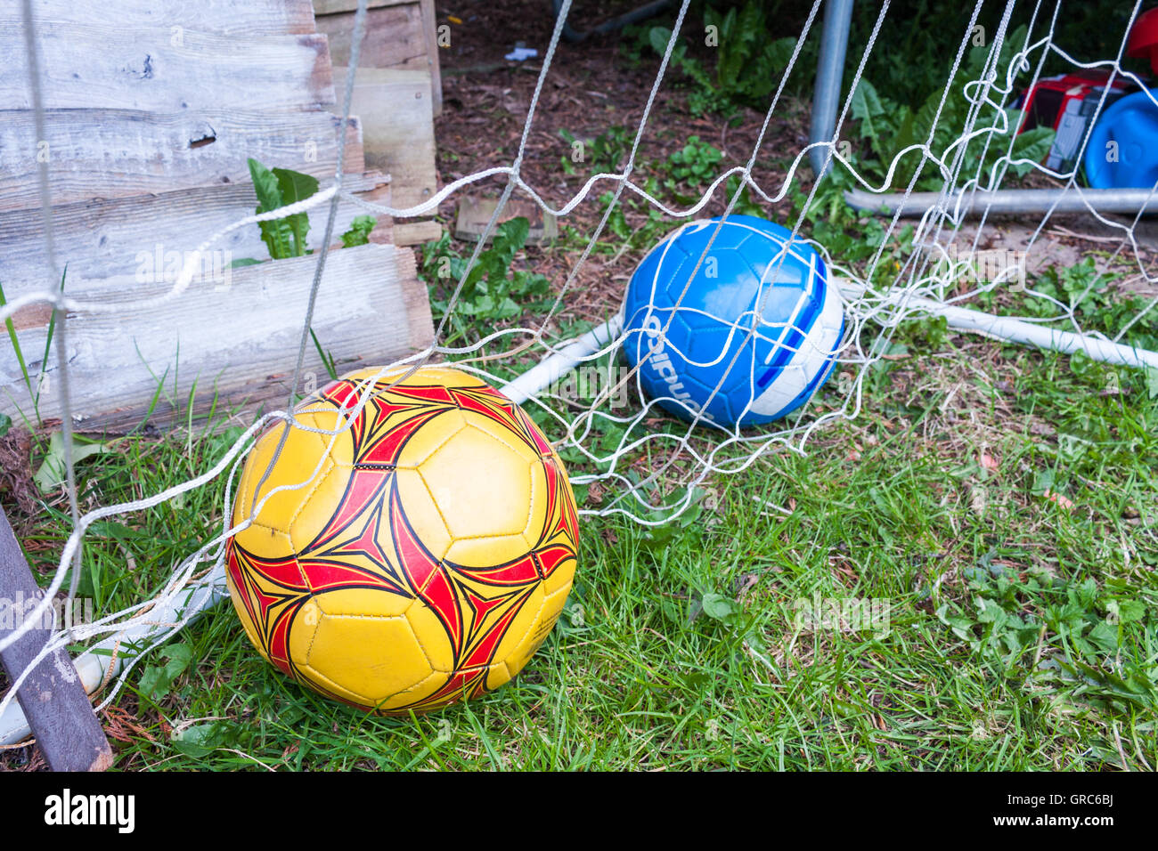 A yellow and a blue football in the back of a child's goal Stock Photo ...