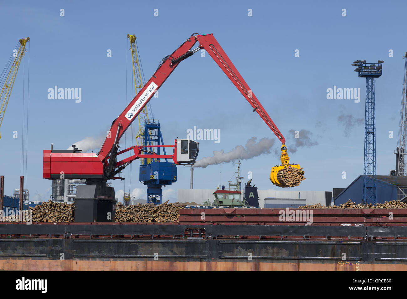 Large Red Excavator Unloads Timber From A Cargo Freighter In Port Of ...