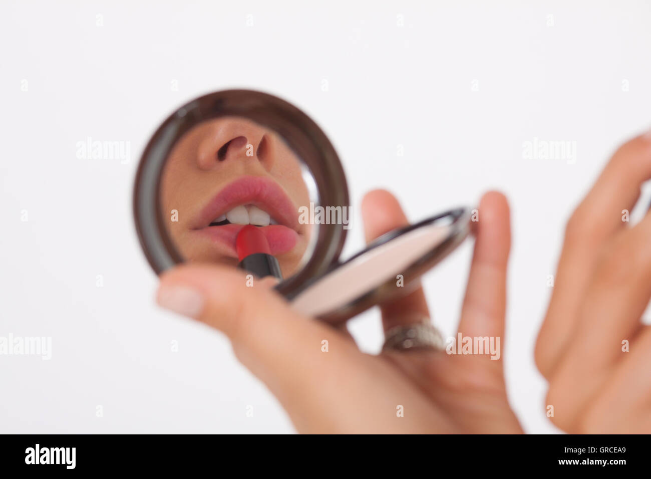 Young Woman In Makeup Mirror, Putting On Lipstick Stock Photo - Alamy