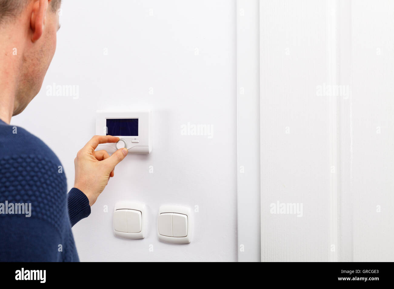 Men regulate temperature on control panel of central heating at wall in ...