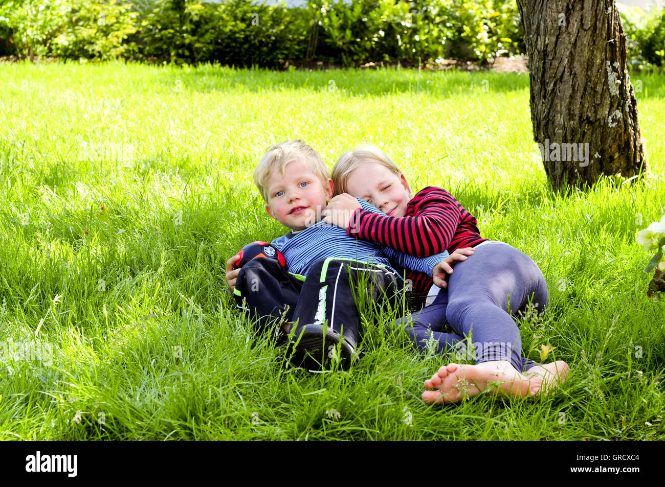 Sister And Brother Lying And Embracing In The Garden Stock Photo - Alamy