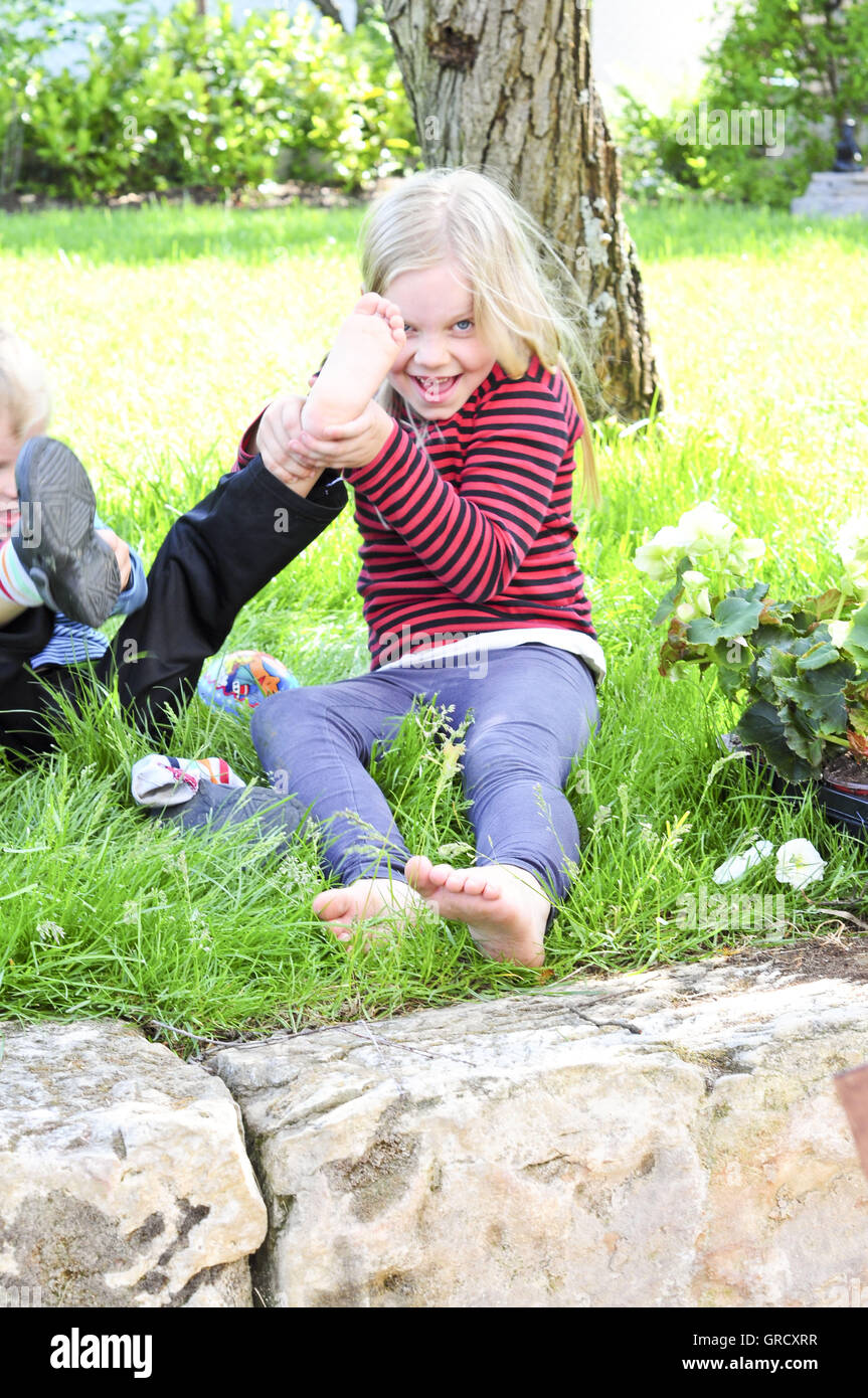 Blond Girl Fooling Around In The Garden Stock Photo - Alamy